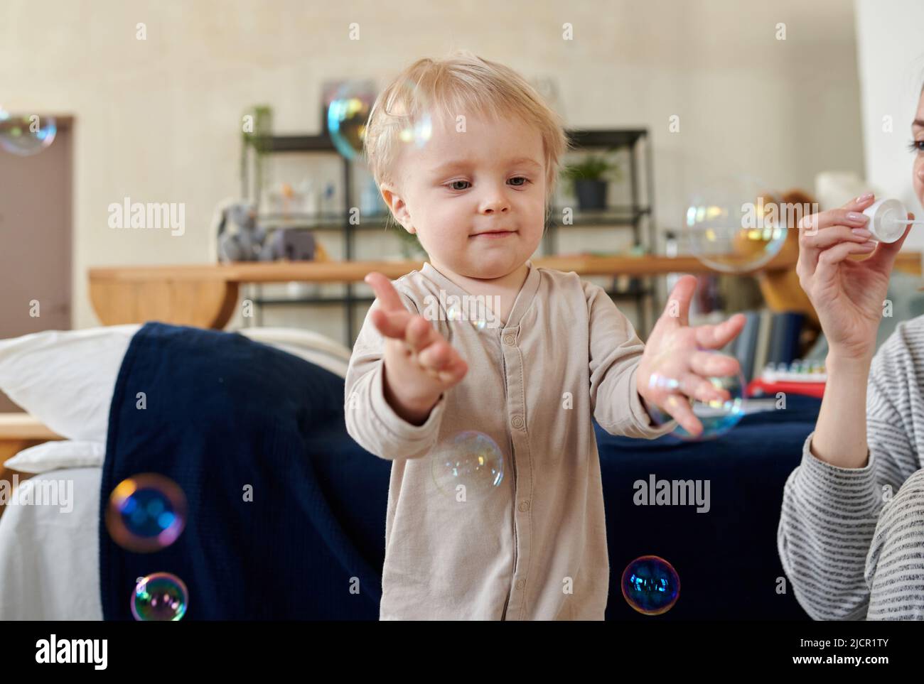Cute kid catching soap bubbles with his hands while playing his mom in ...