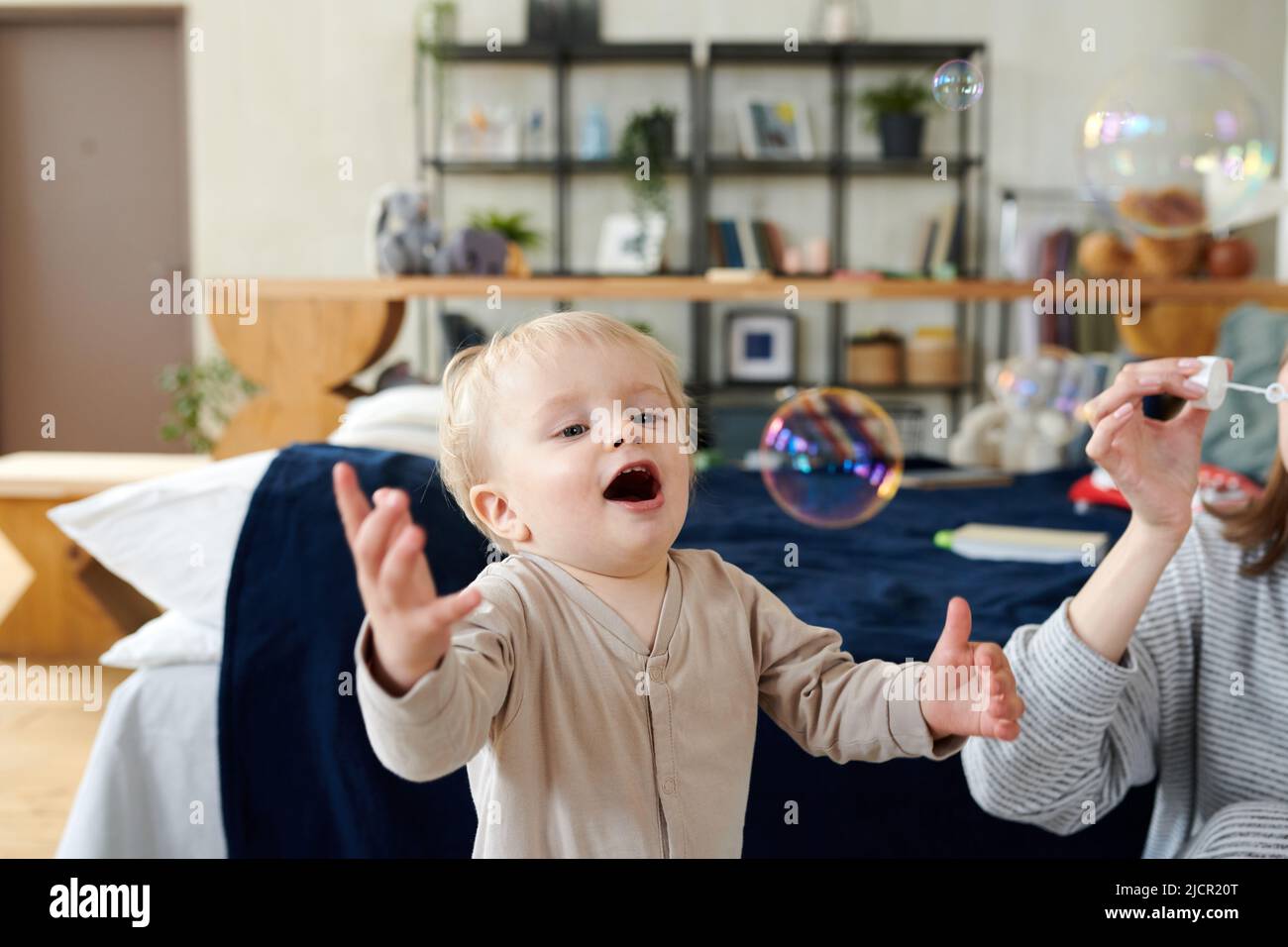 Adorable little kid catching soap bubbles blowing by his mom in the ...
