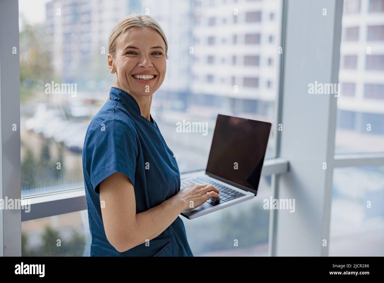 Smiling female healthcare worker using laptop while working at doctor's ...