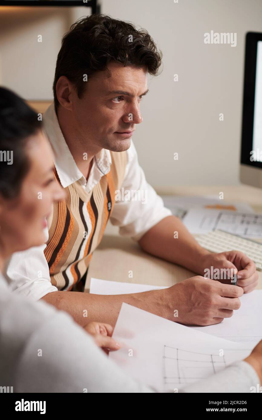 Team of serious architects talking to clients at meeting in bureau ...