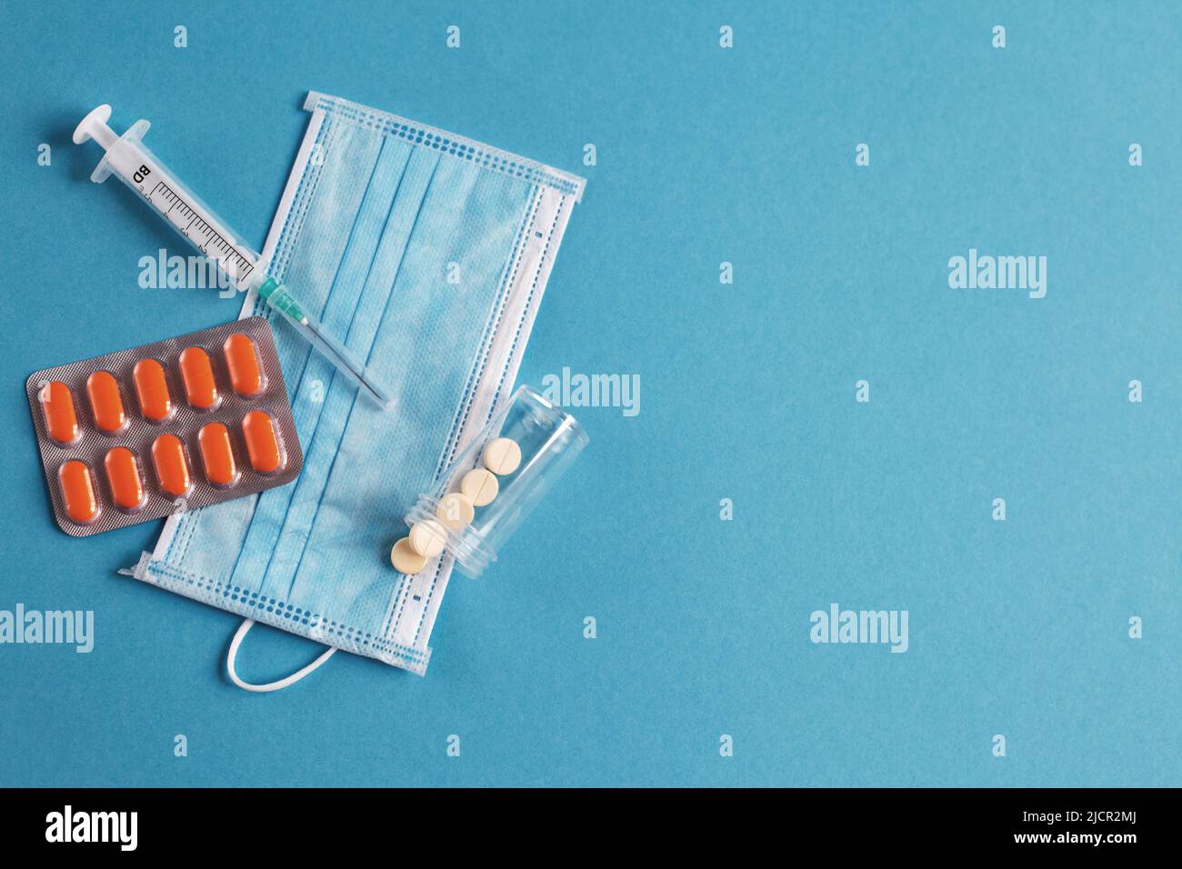 White medical mask, syringe, tablets and vials with medicine on the ...