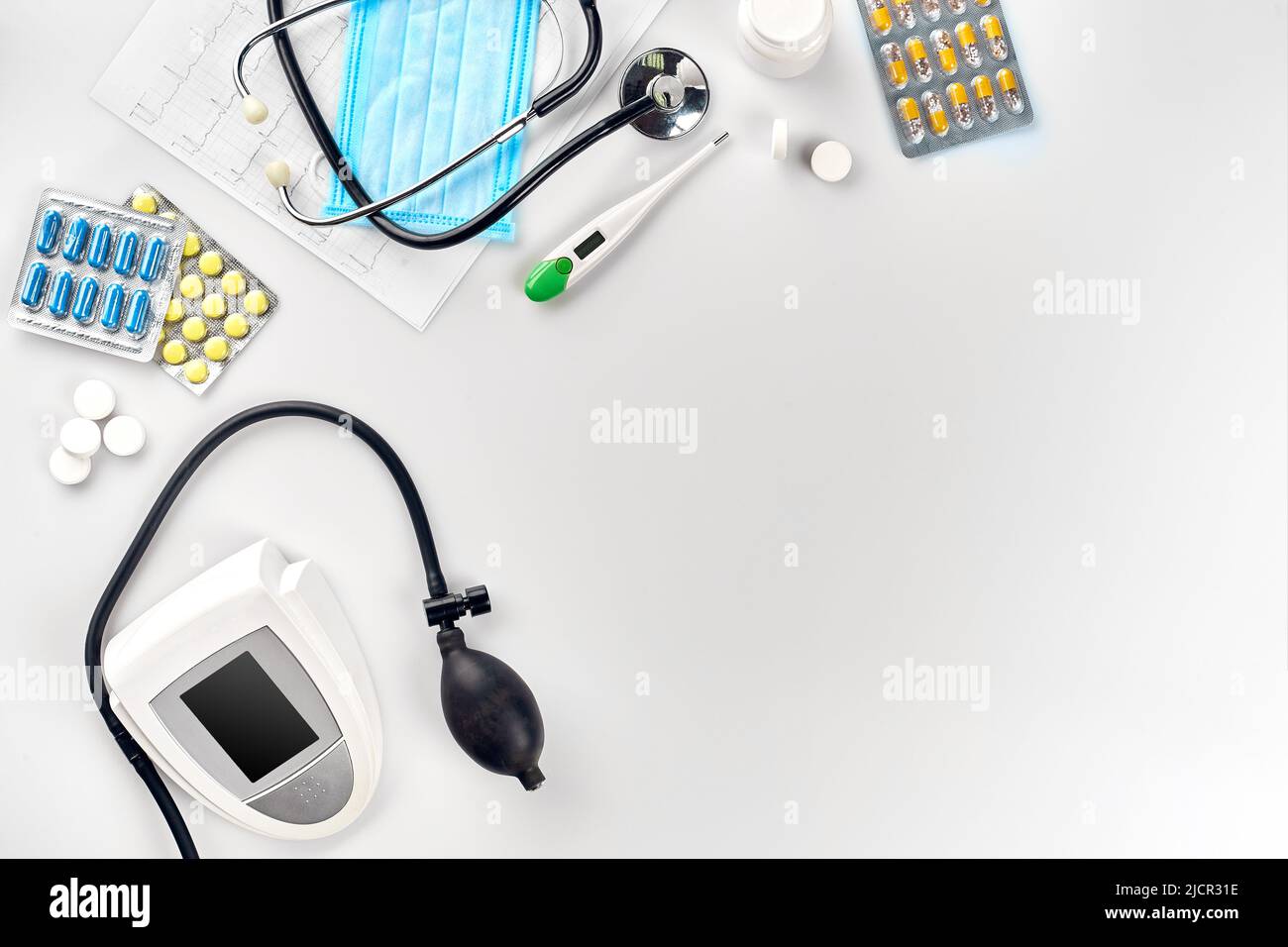 White electric tonometer with stethoscope, multicolored pills, mask and ...