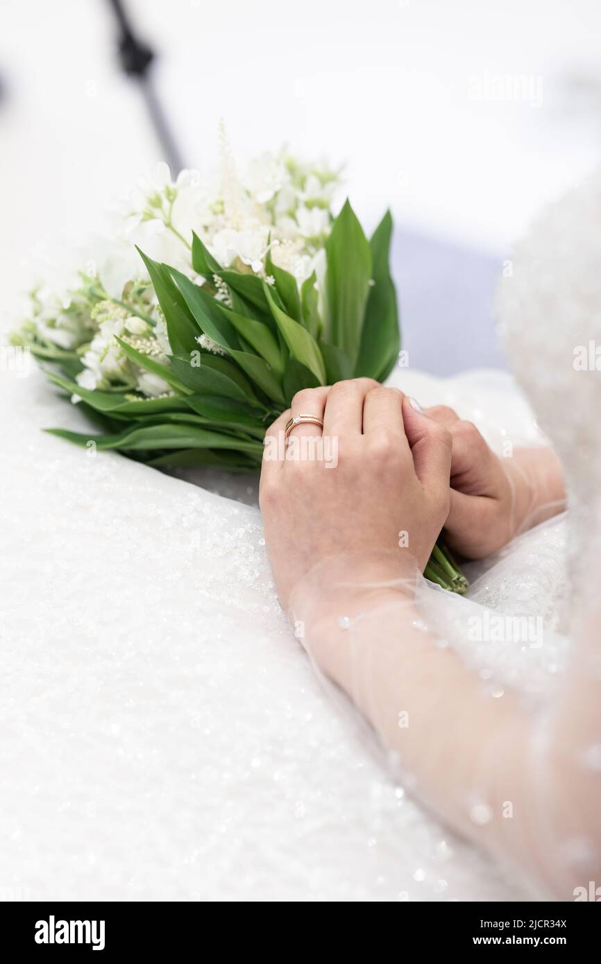 Bride sitting with a bouquet in the waiting room, Focus on wedding ring ...