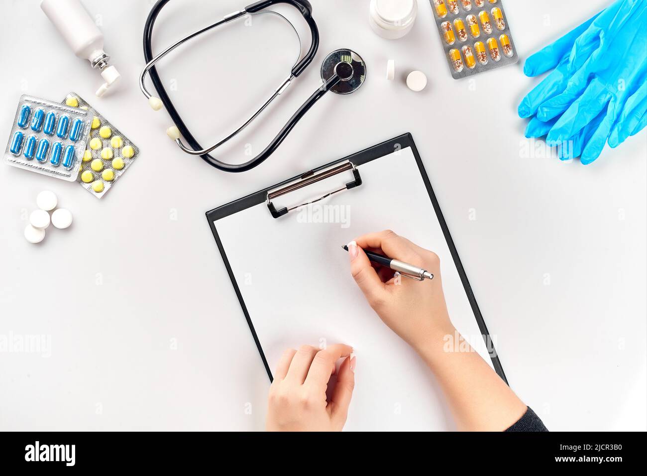 Female doctor's hand filling the medical record on white table Stock ...