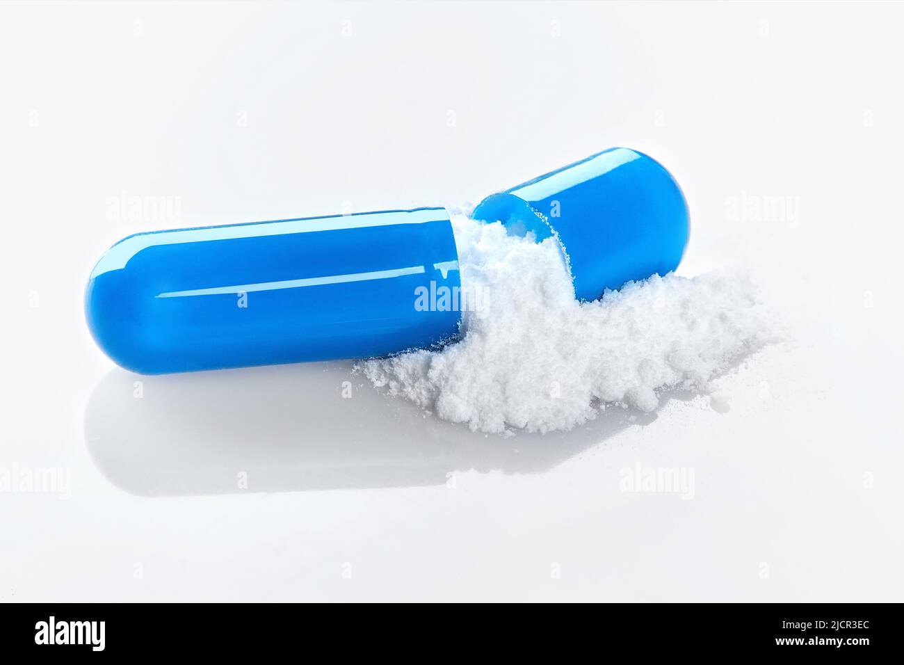 Single blue capsule on white background. Contents of the medical ...