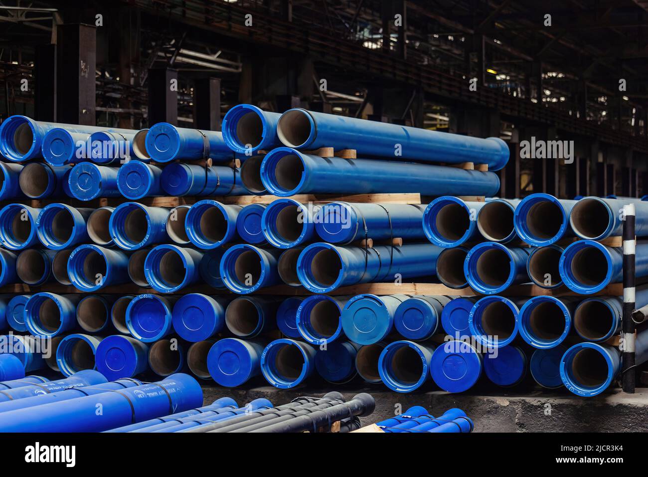 New blue colored cast iron pipes with caps for pipeline construction in ...