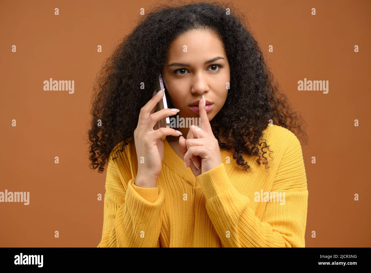 Young multiracial lady has phone conversation and showing shout gesture ...