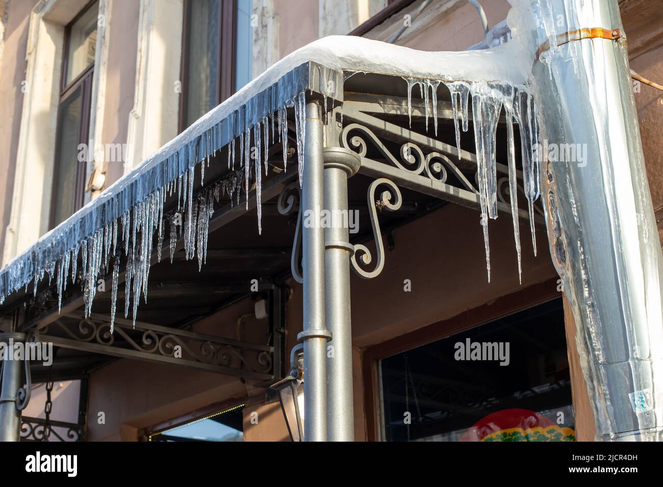 Sharp icicles a lot and melted snow hanging from eaves of roof and ...