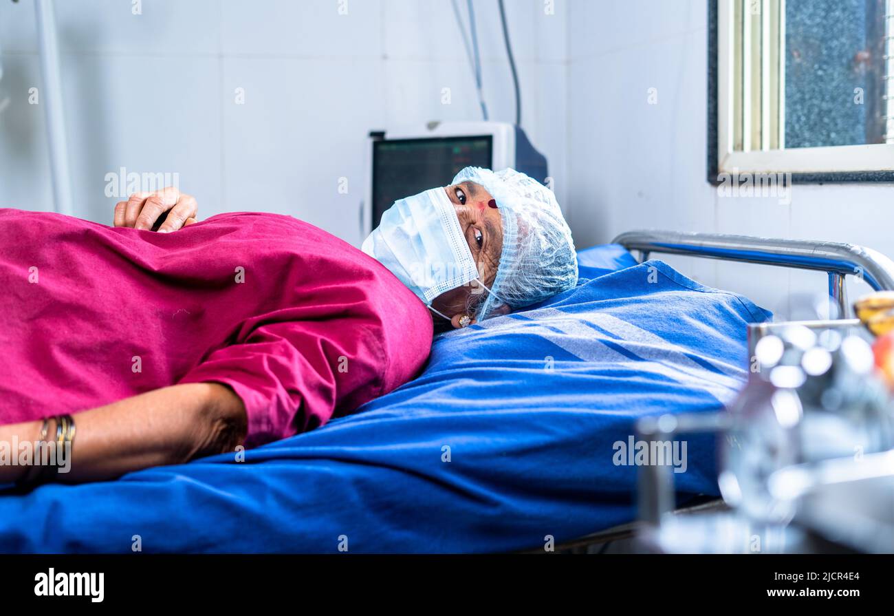 Senior sick patient on hospital bed with medical face mask and ...