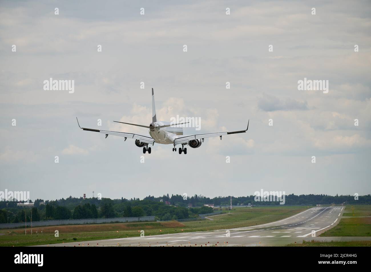 Commercial airplane flying in the sky at cloudy weather. Back view of ...