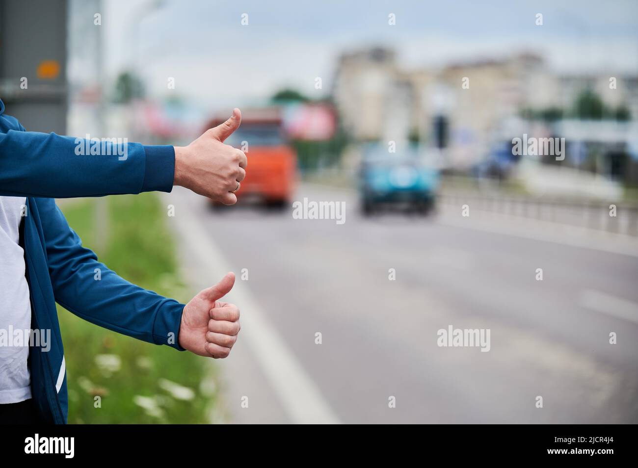 Close up of two man's hands hitchhiking by roadside. Male hands showing ...