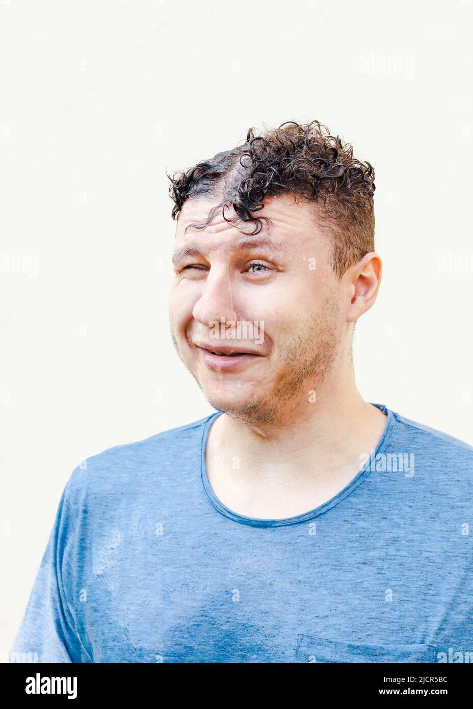 Astonished Shocked Wet Young Caucasian Man With Curly Hair In Blue T