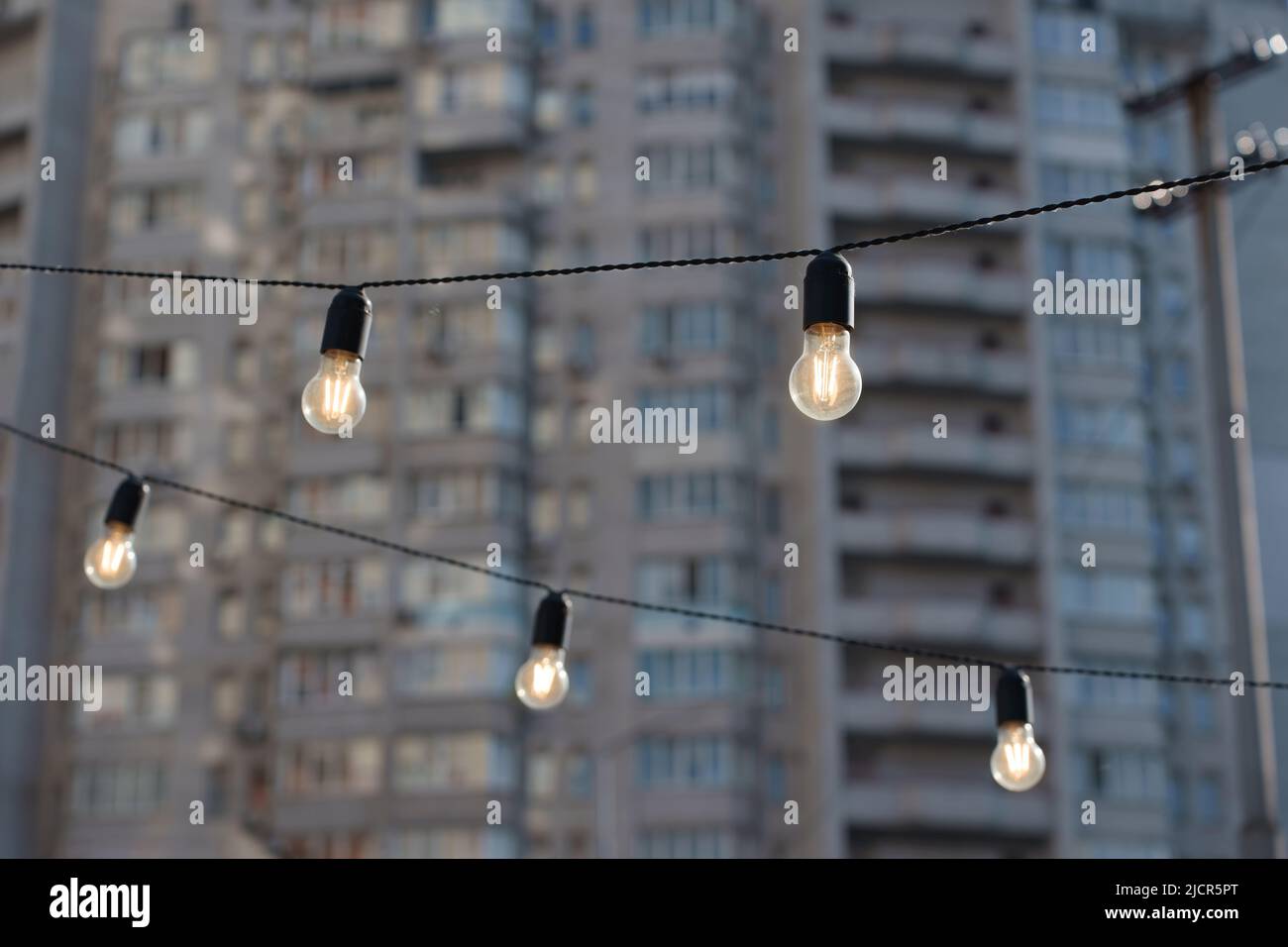 Light bulbs on wire against a residential building background Stock ...