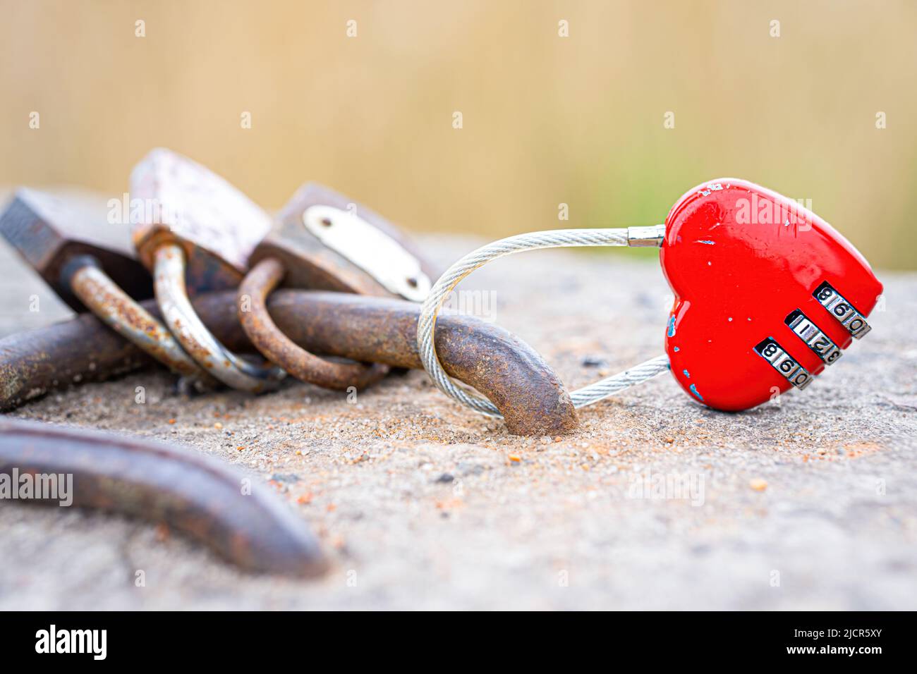 Weathered heart shaped lock among standard rusty padlocks. Love and ...