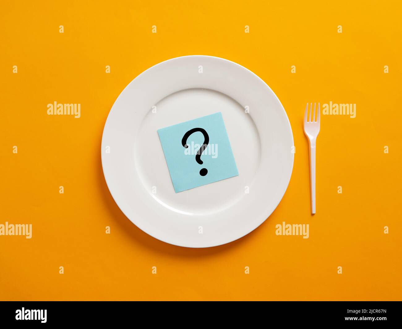 Notepaper with question mark symbol on a white plate with yellow ...