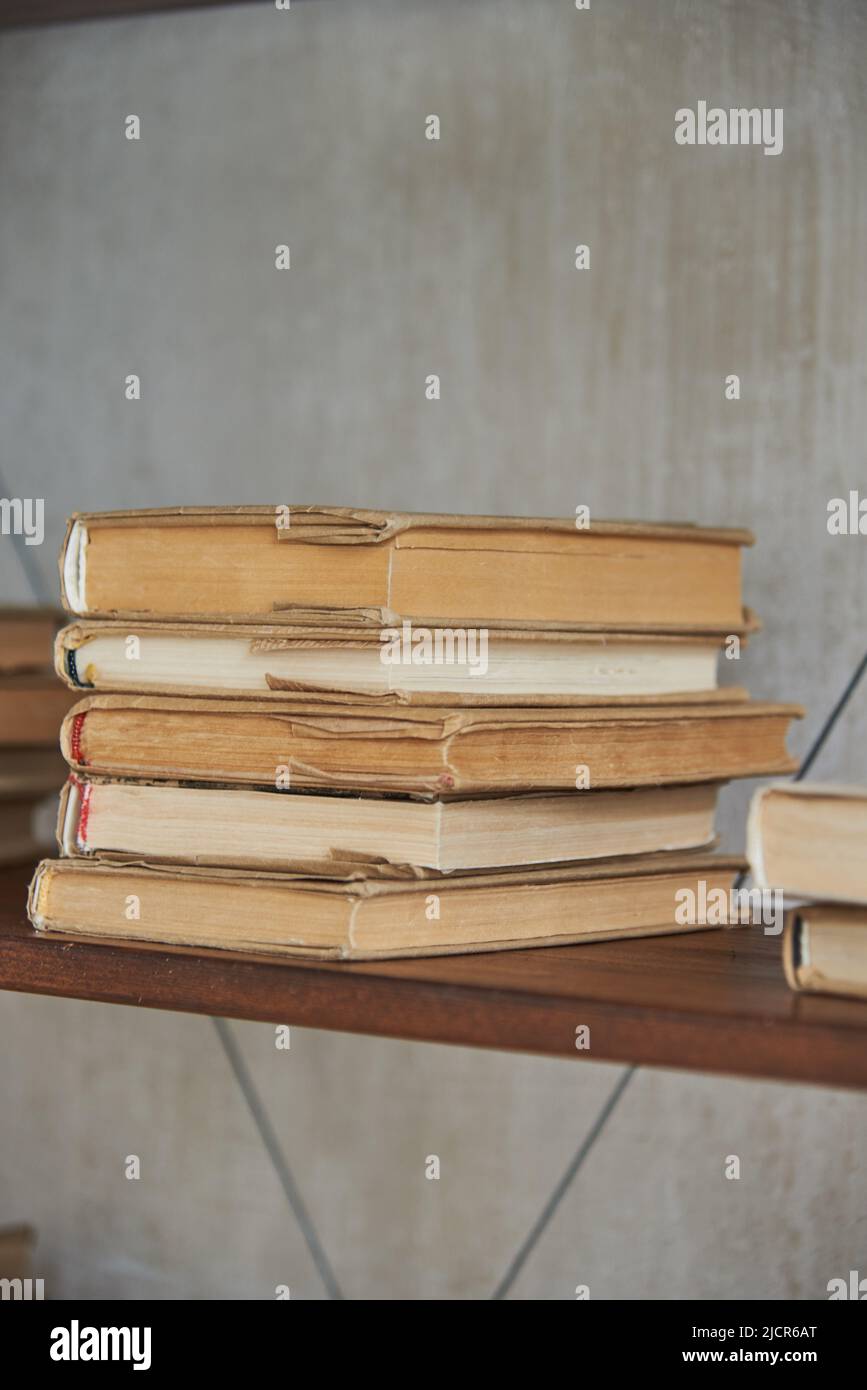 A stack of old books on a shelf against a gray wall Stock Photo - Alamy