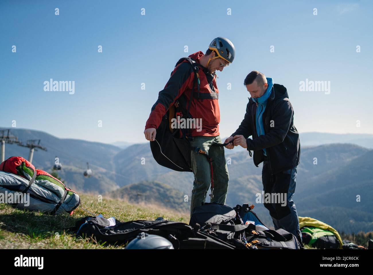 Man helping paragliding pilot to prepare for flight Stock Photo - Alamy