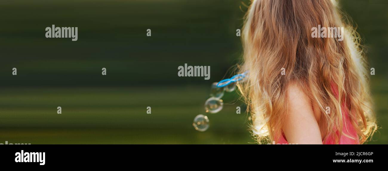 Cute little girl is blowing a soap bubbles back. banner Stock Photo - Alamy