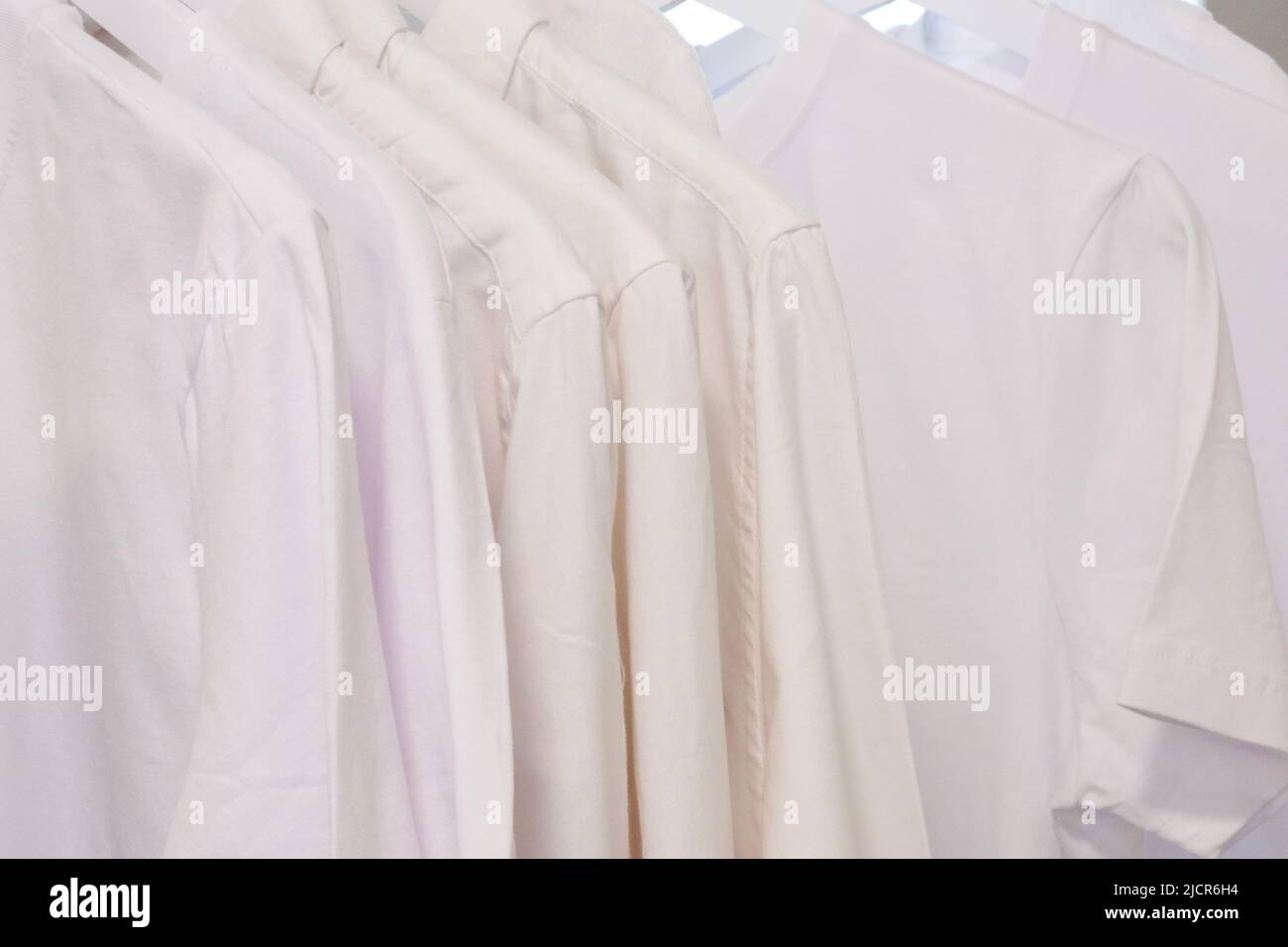 White clothes closeup hanging on white hangers Stock Photo - Alamy
