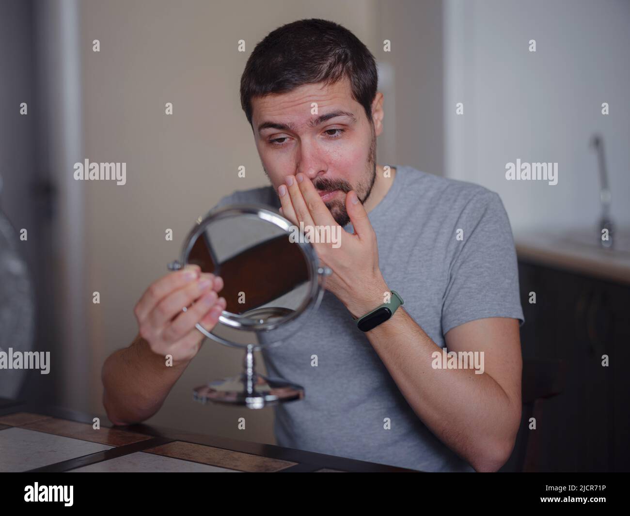 guy checking his skin. Young man looking in mirror touches face with ...