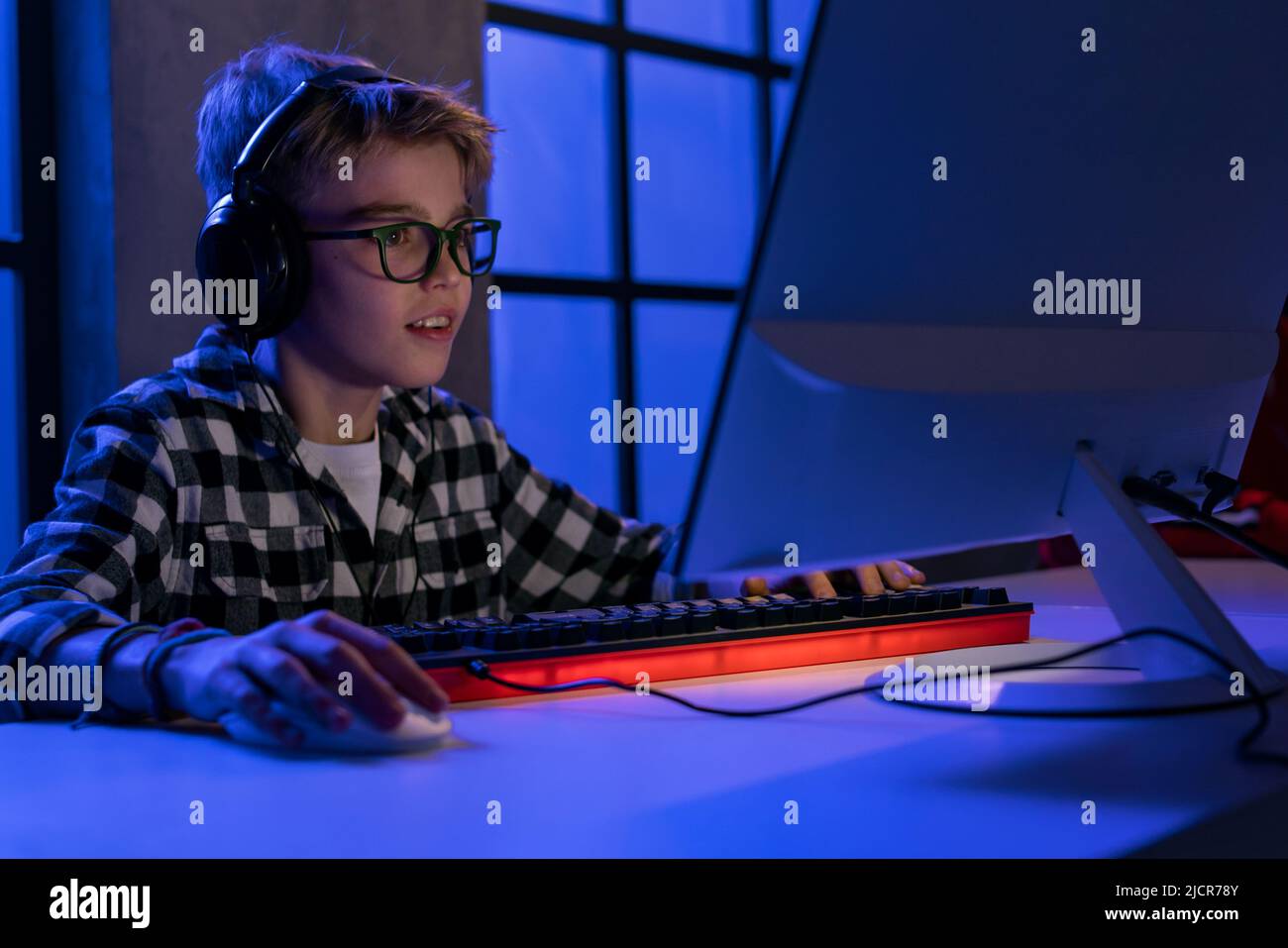 Young gamer boy with headphones playing computer video game Stock Photo ...