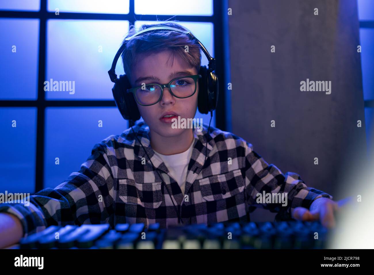 Young gamer boy with headphones playing computer video game Stock Photo ...