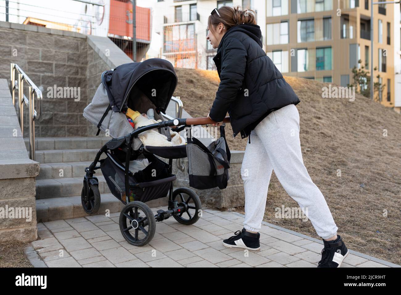 a young mother tries with a baby stroller to drive up the stairs Stock ...