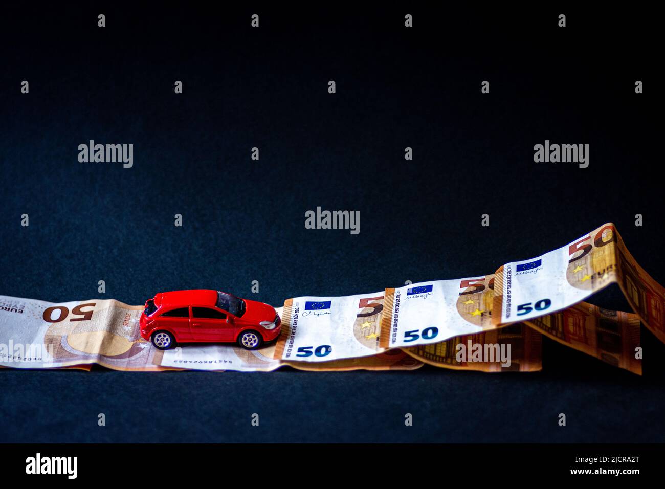 small red car toy on 50 euro banknotes on black background Stock Photo ...