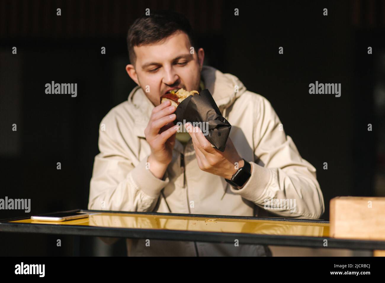Handsome man having traditional hot dog cuisine during rest break ...
