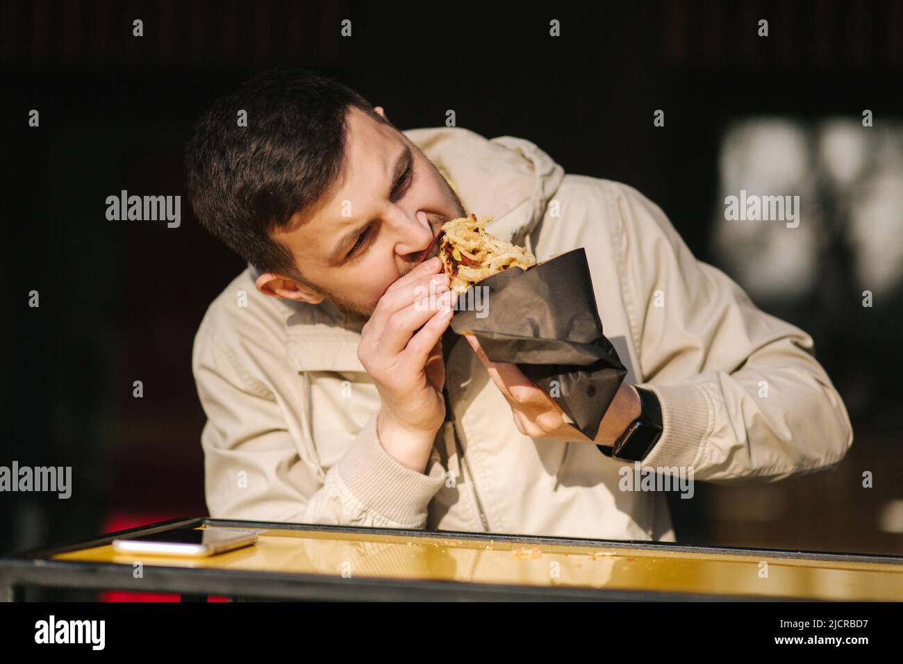 Handsome man having traditional hot dog cuisine during rest break ...