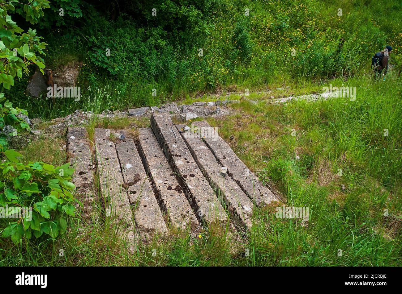 Walker passing concrete railway sleepers over a very deep and old lead ...
