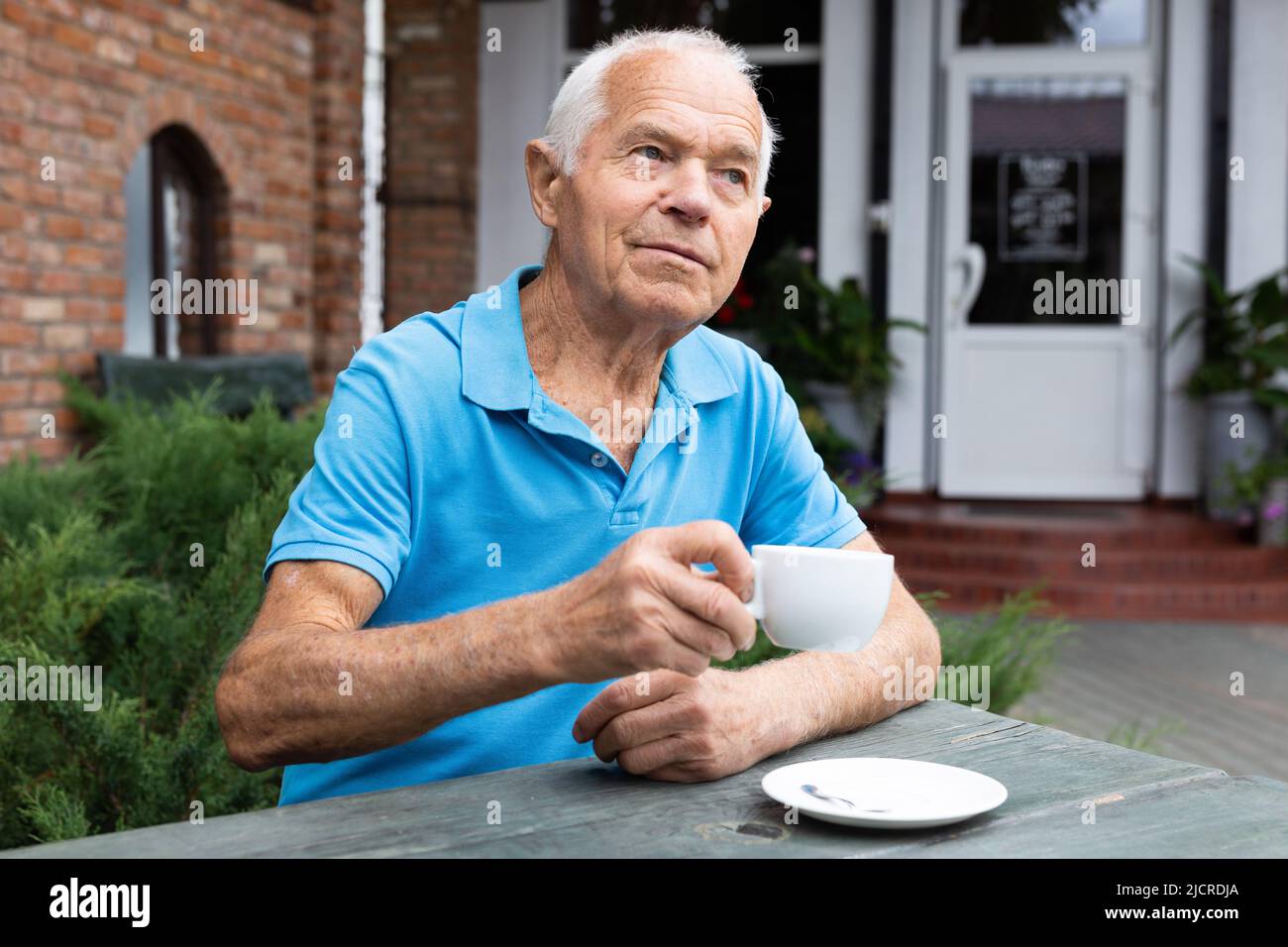 Old man sitting at table in outdoor cafe and drinking tea Stock Photo ...