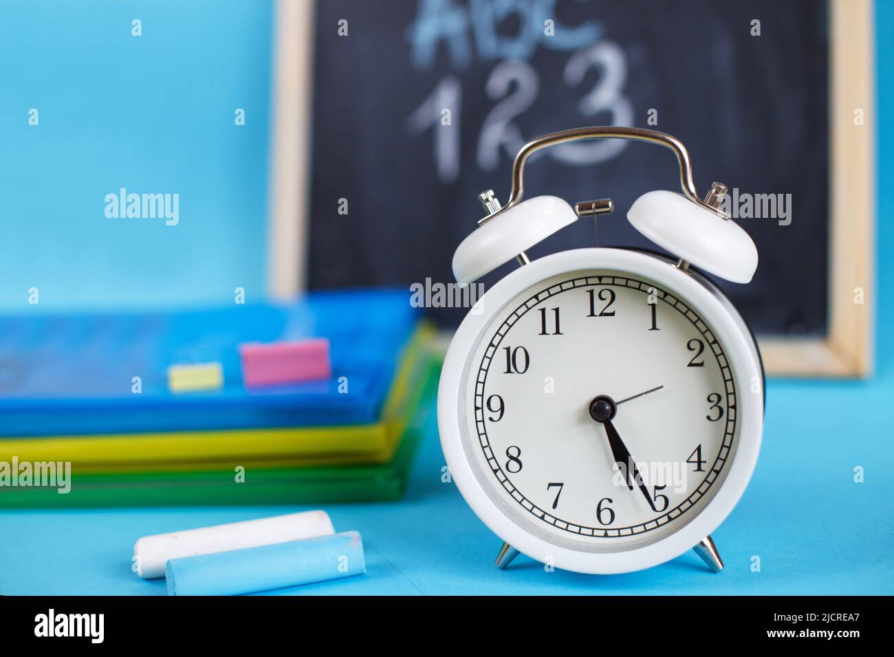 Textbooks and alarm clock on a blue background. Back to school. Library ...