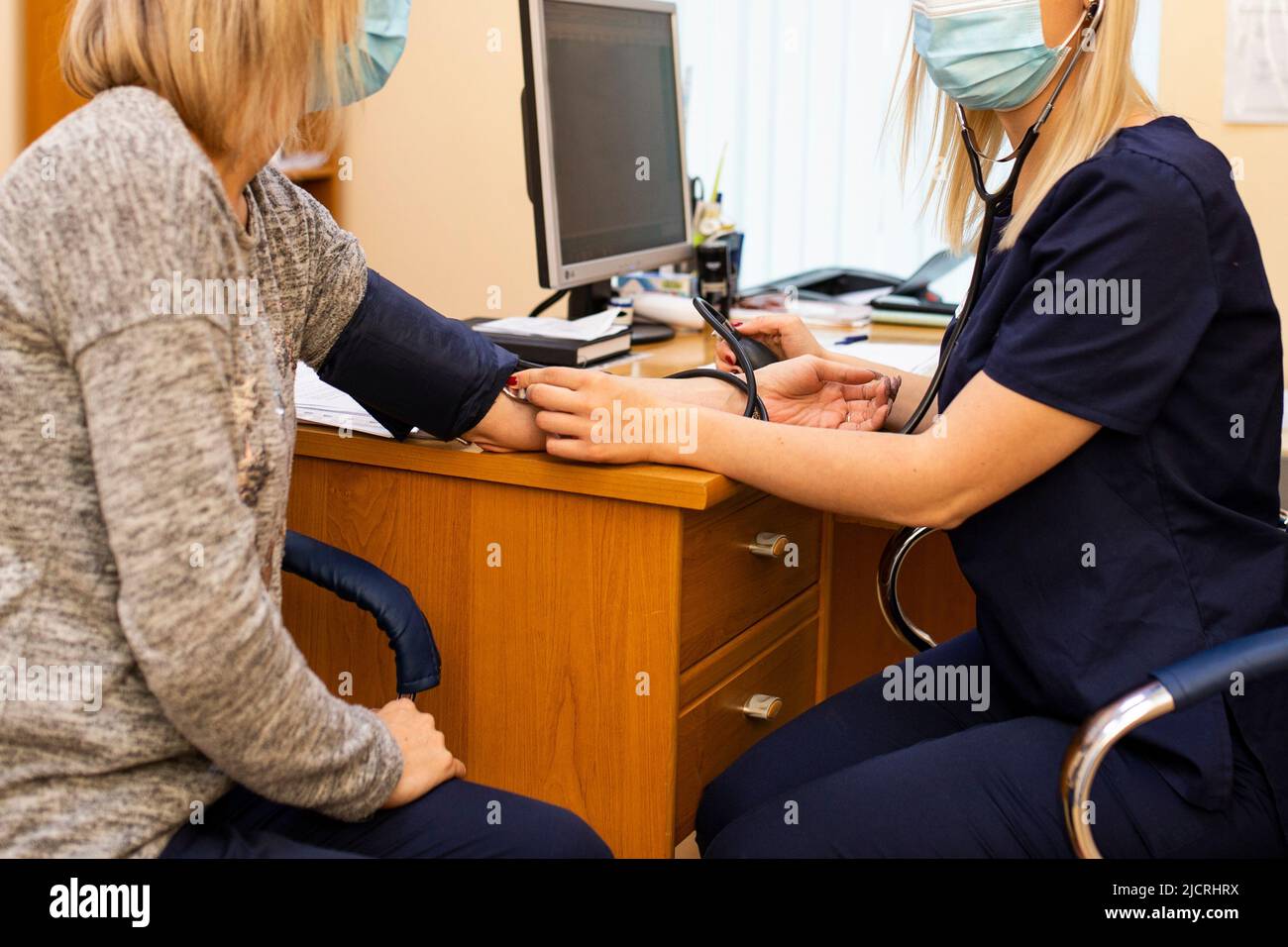 a nurse in uniform measures the pressure of a patient with a tonometer ...
