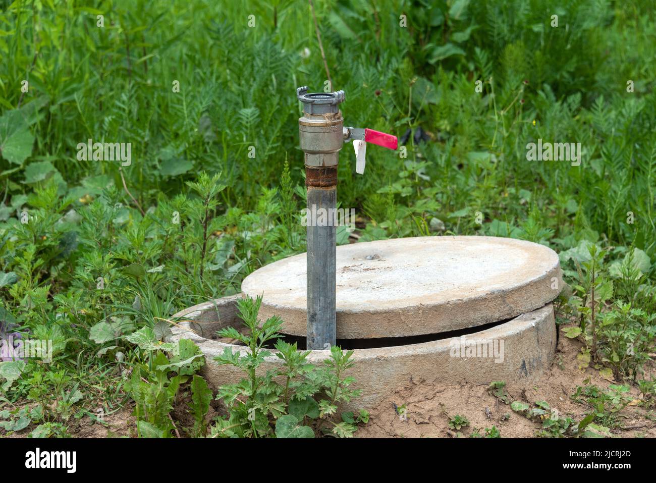 Technical concrete well with a pipe and a lever for water supply. Water ...