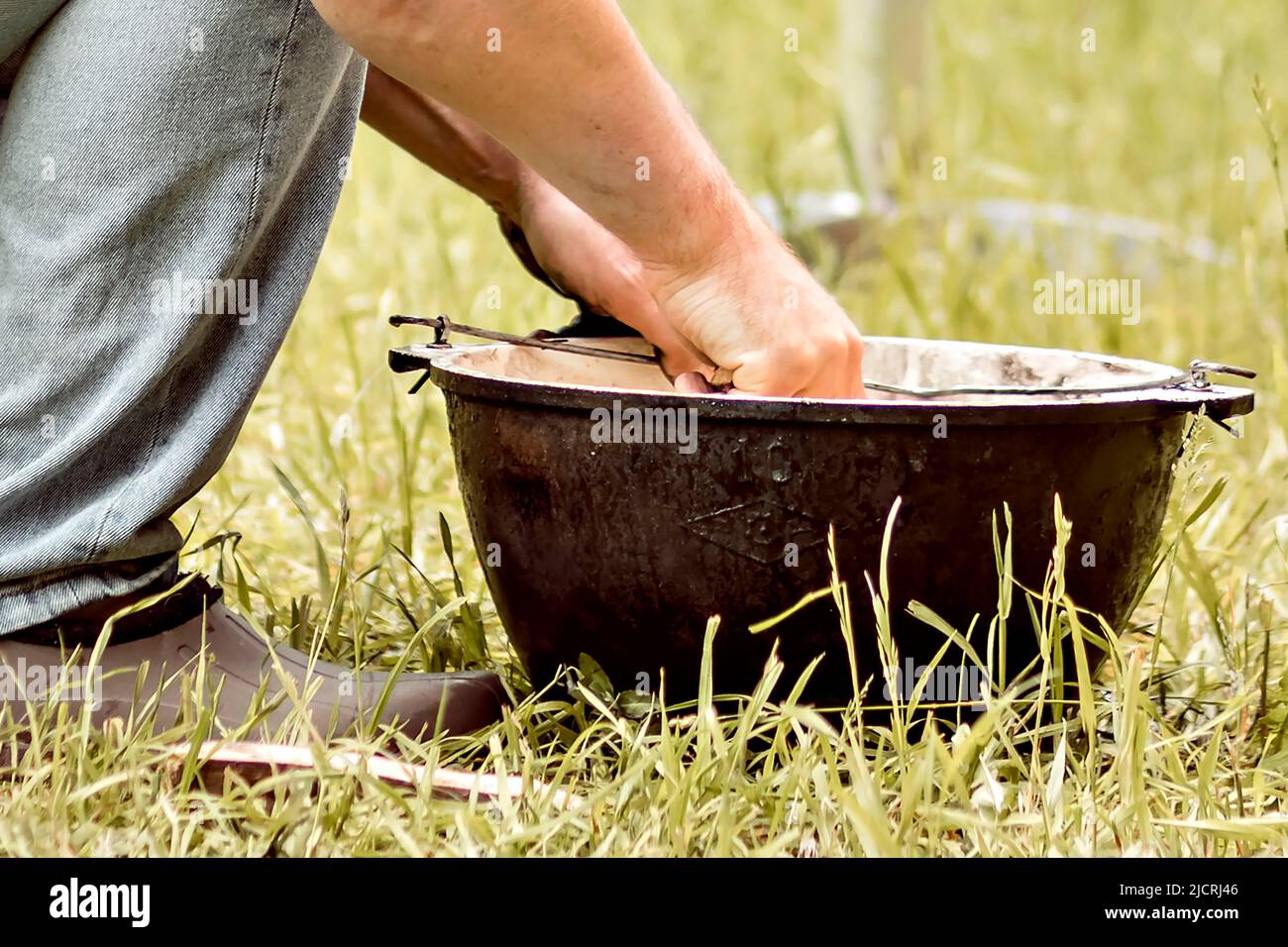 A man does his homework, cleans a cauldron in the backyard of a country ...
