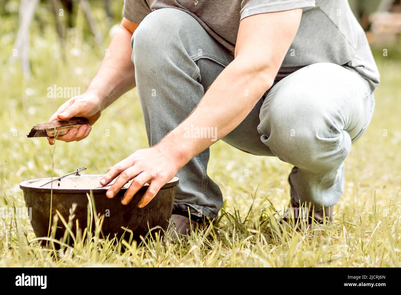 A man does his homework, cleans a cauldron in the backyard of a country ...