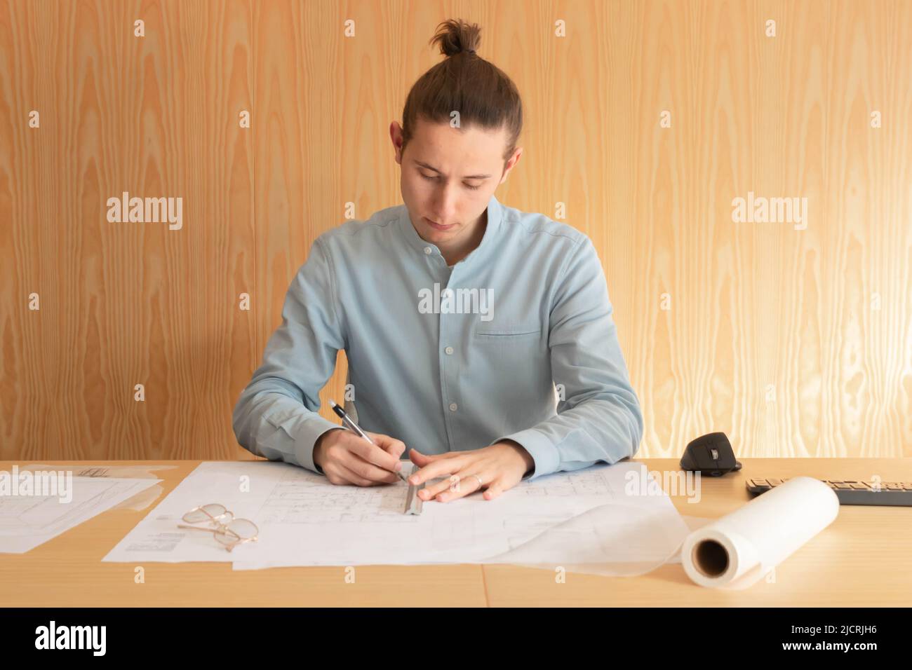 Portrait of young architect working on a project hand drafting at ...