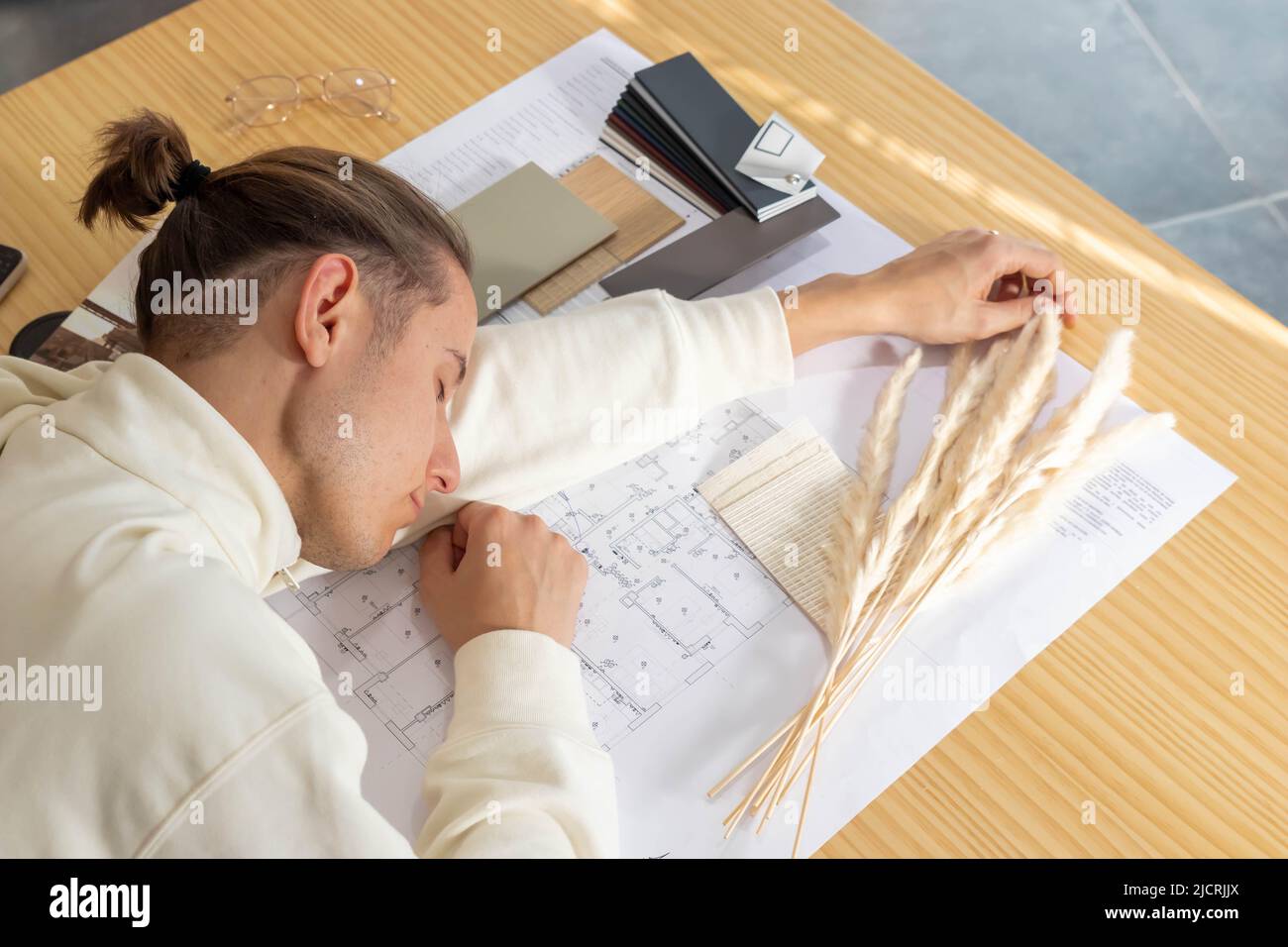 Young man sleeping on desk during work of architecture and interior ...