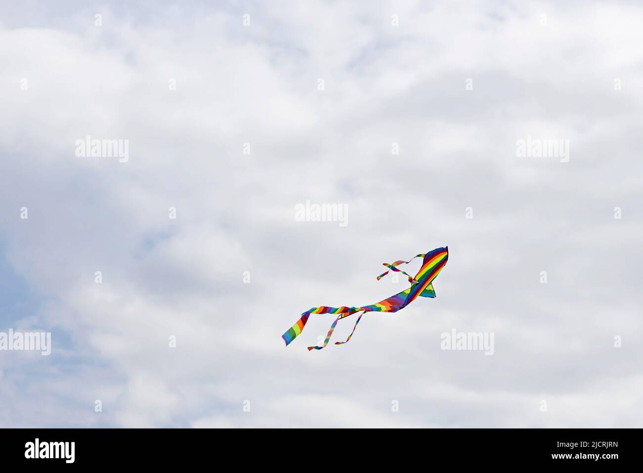 Colorful blue sky with white fluffy clouds and a flying colored kite ...