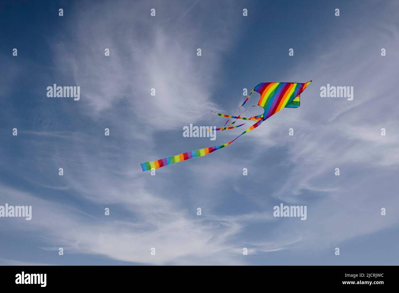 Colorful blue sky with white fluffy clouds and a flying colored kite ...