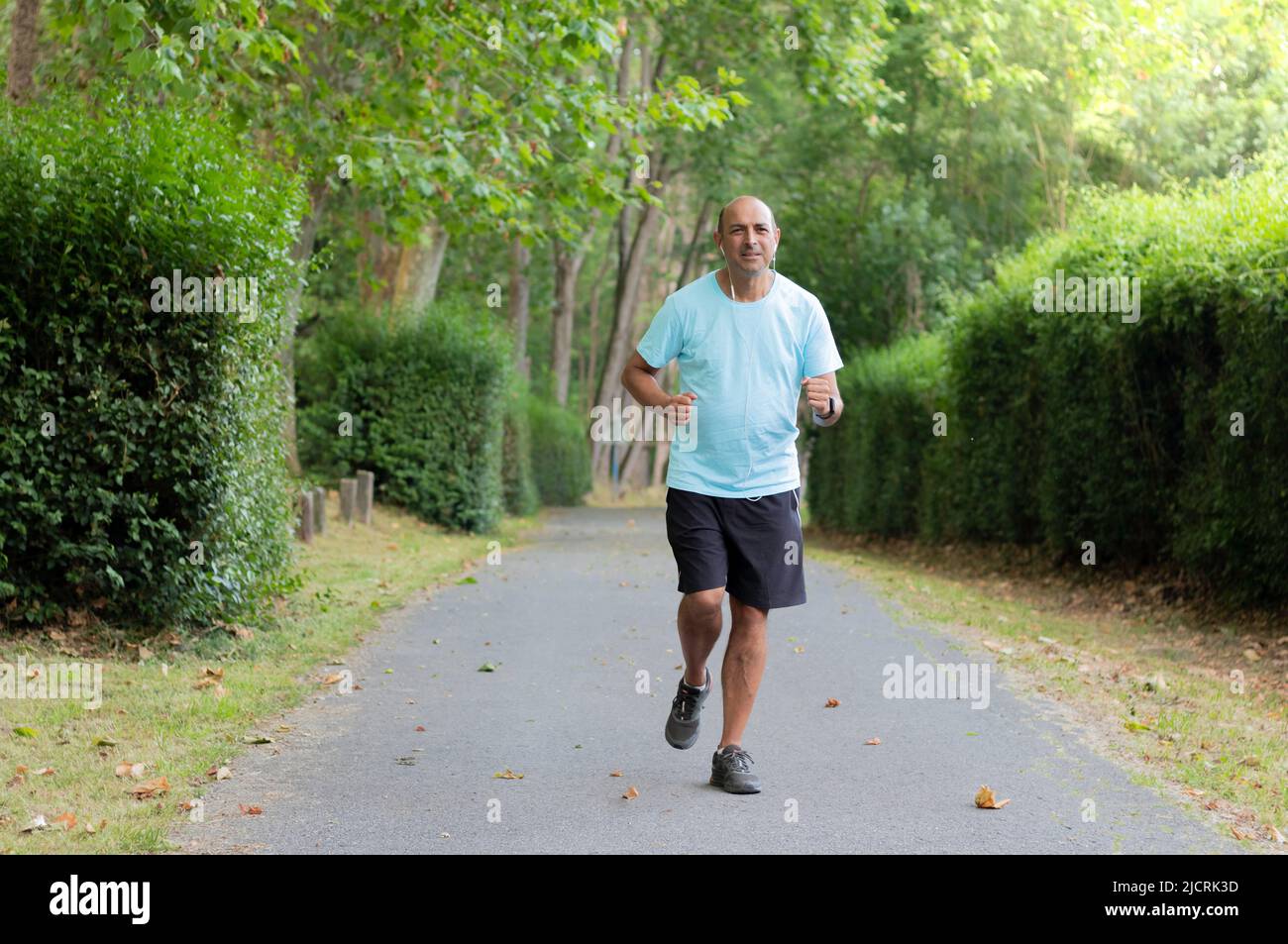 Front portrait in landscape format of an older man running along a path ...