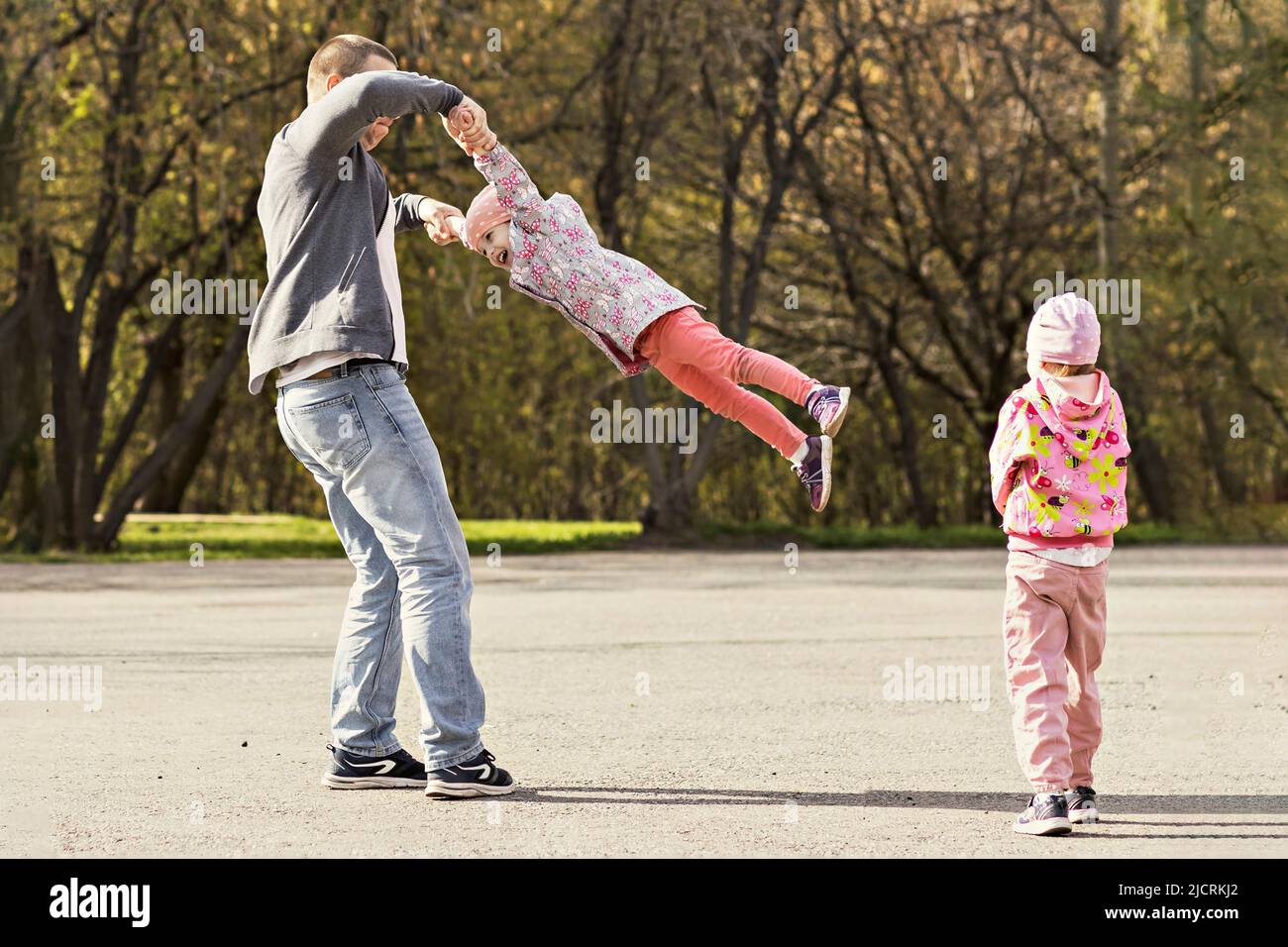 Dad plays with his daughters in the park. Twirling a girl around ...