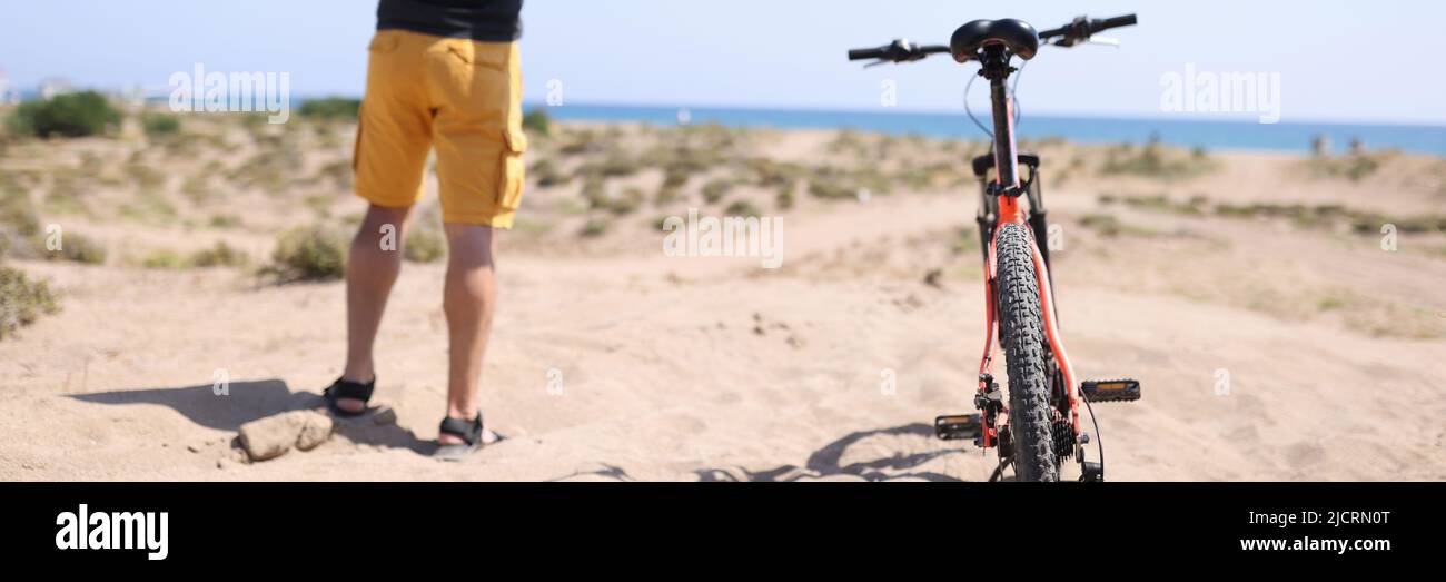 Man standing on beach near bicycle with his arms wide apart back view ...