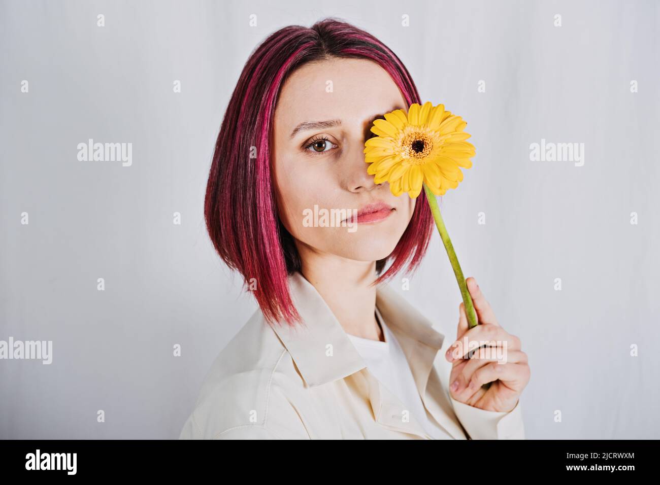 Studio portrait millennial woman with bright red Color hair and yellow ...