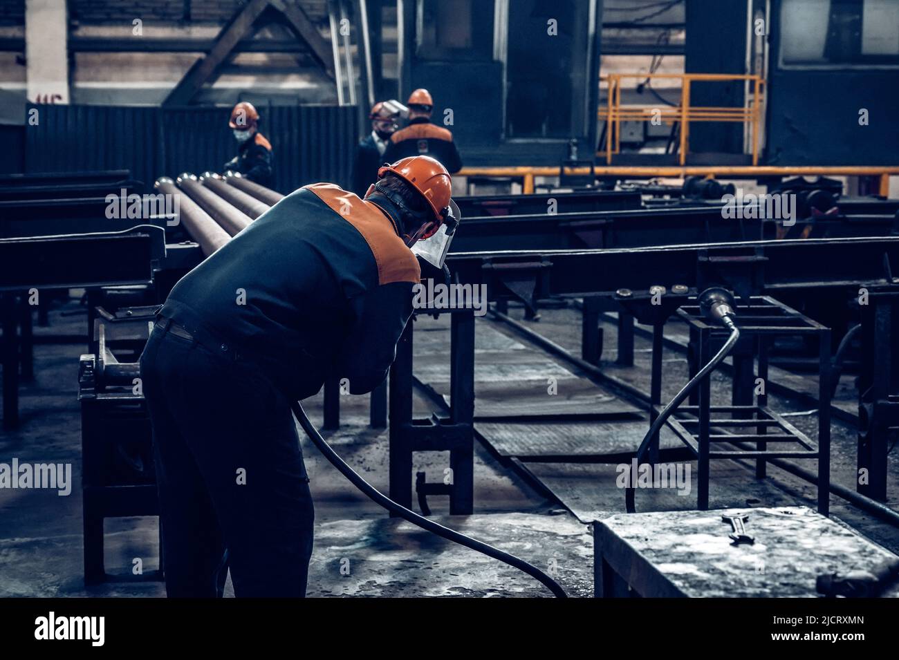 Worker at steel factory. Process of making steel pipes under hot ...