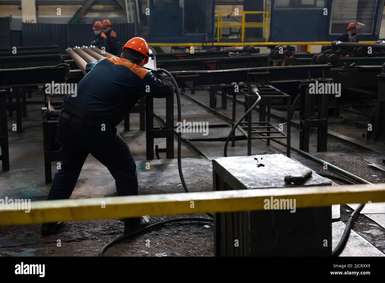Worker at steel factory. Process of making steel pipes under hot ...