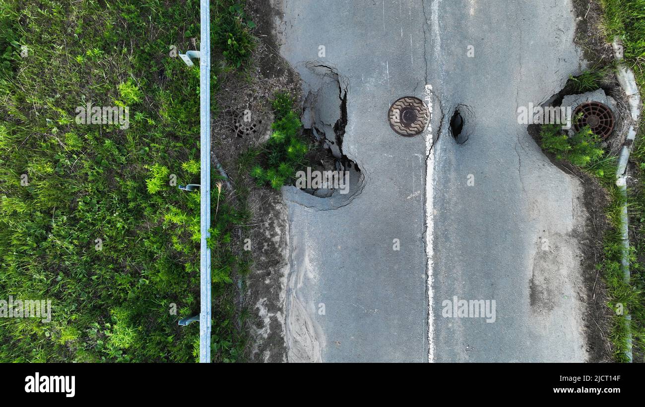 Broken old asphalt road outside the city. Pits and potholes. Aerial ...