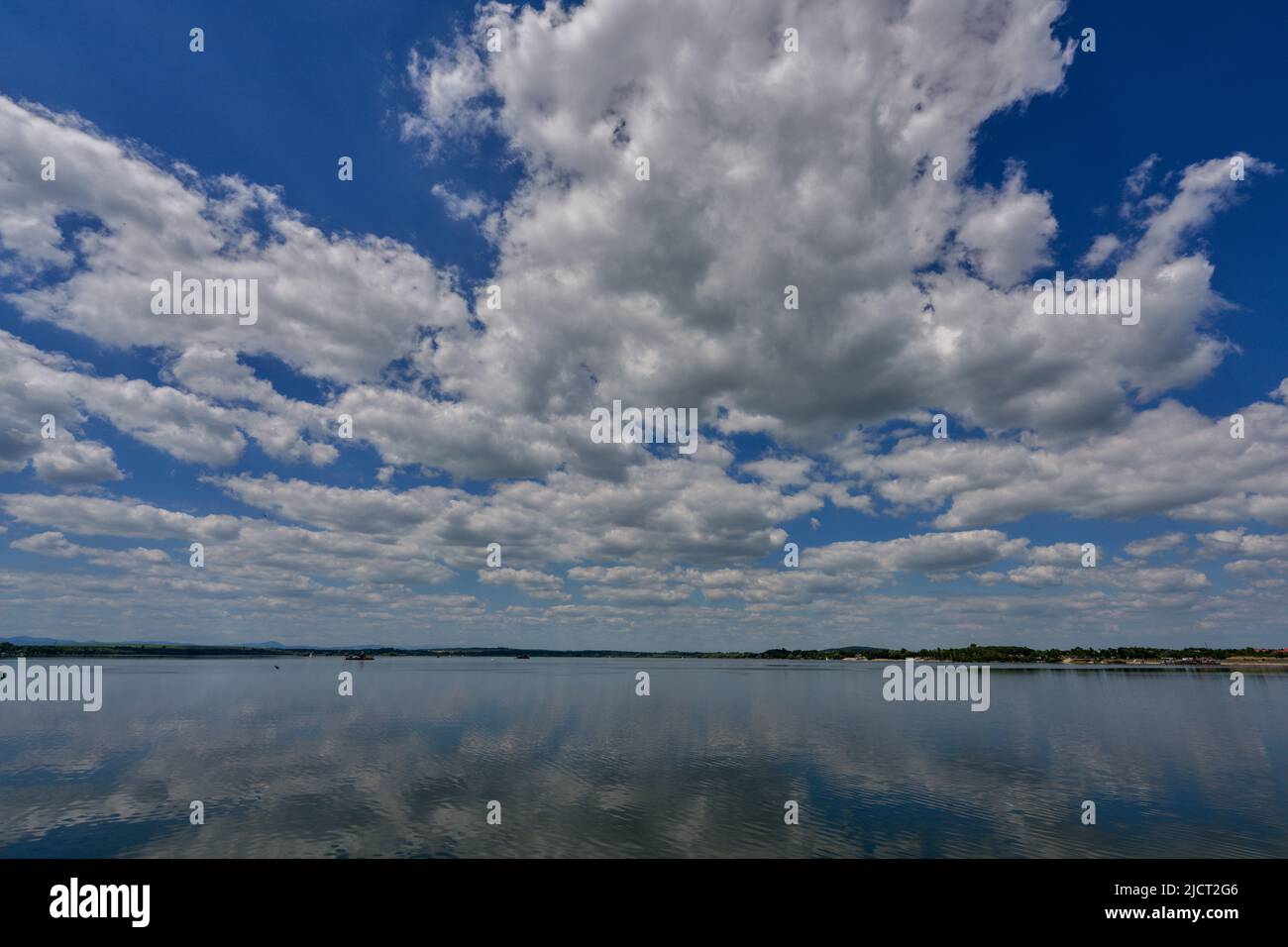 Blue sky with white clouds reflecting on the water Stock Photo - Alamy