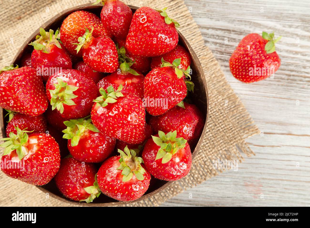 Fresh juicy ripe red strawberry in a brown coconut plate. Top view ...
